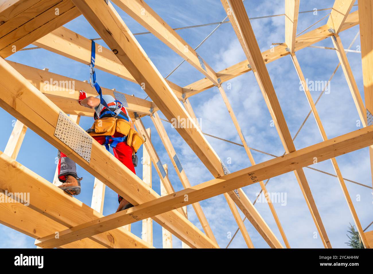 A construction worker is carefully securing wooden beams on a framework ...