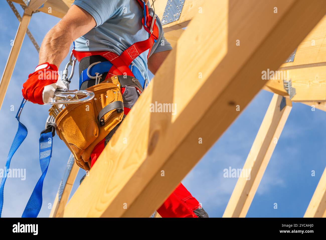 A construction worker is secured with a harness, busy constructing a ...
