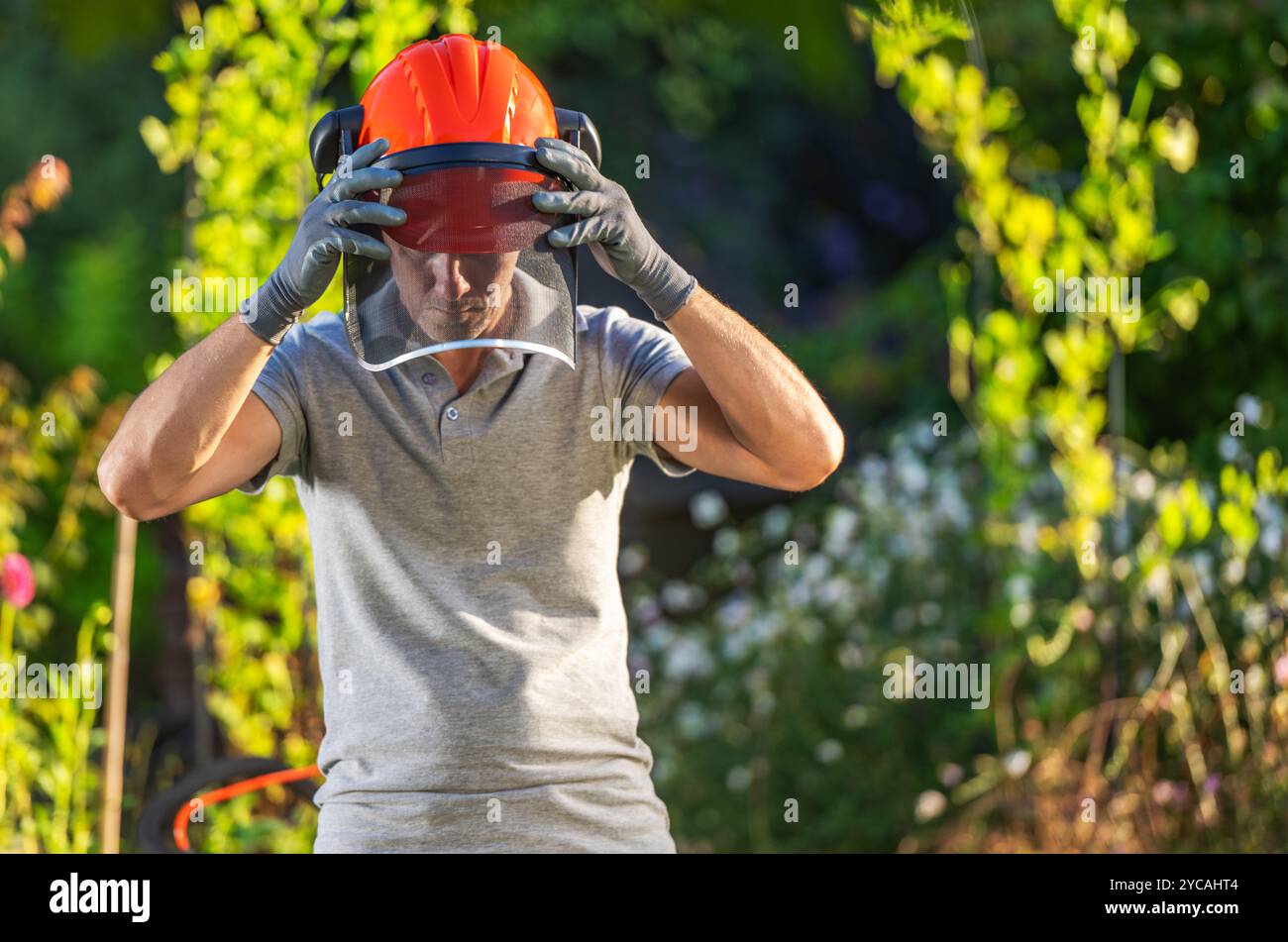 A man adjusts his safety helmet and face shield while readying himself ...