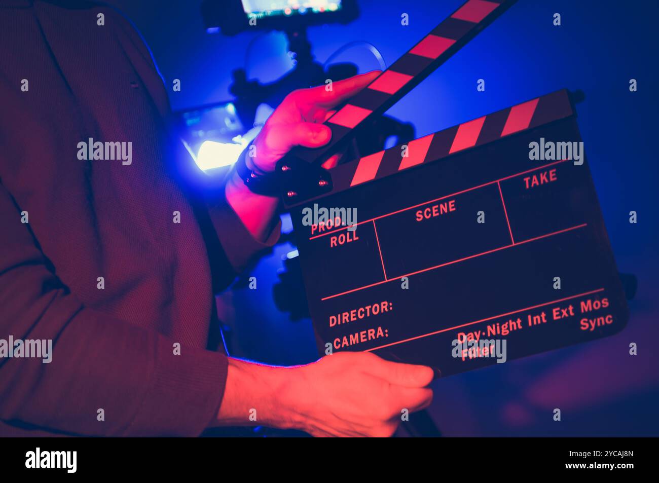 A filmmaker holds a clapperboard labeled with production details ...