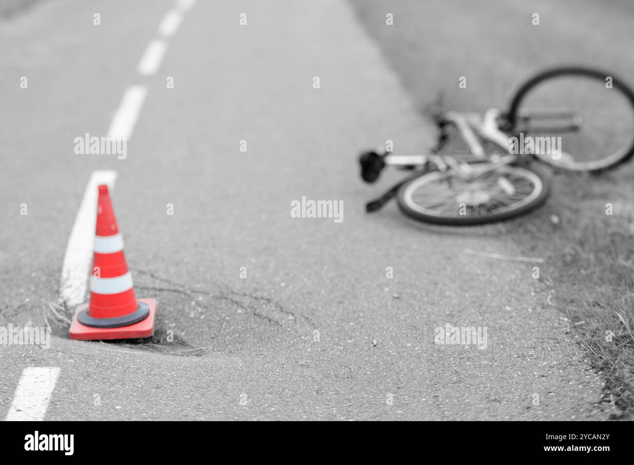 dropped bike, a pothole in asphalt and a traffic cone, selective color ...
