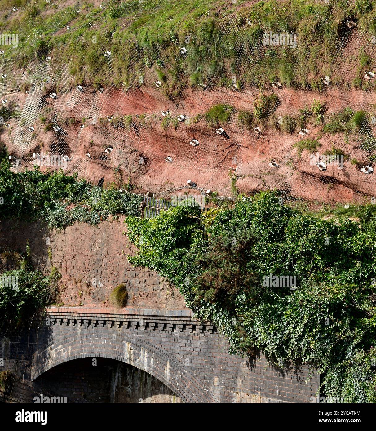 Rock bolts and wire netting supporting unstable red sandstone cliffs ...