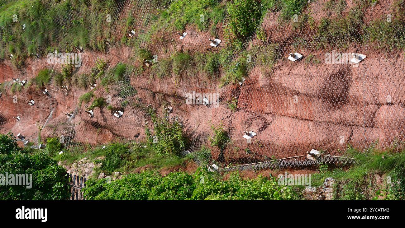 Rock bolts and wire netting supporting unstable red sandstone cliffs ...