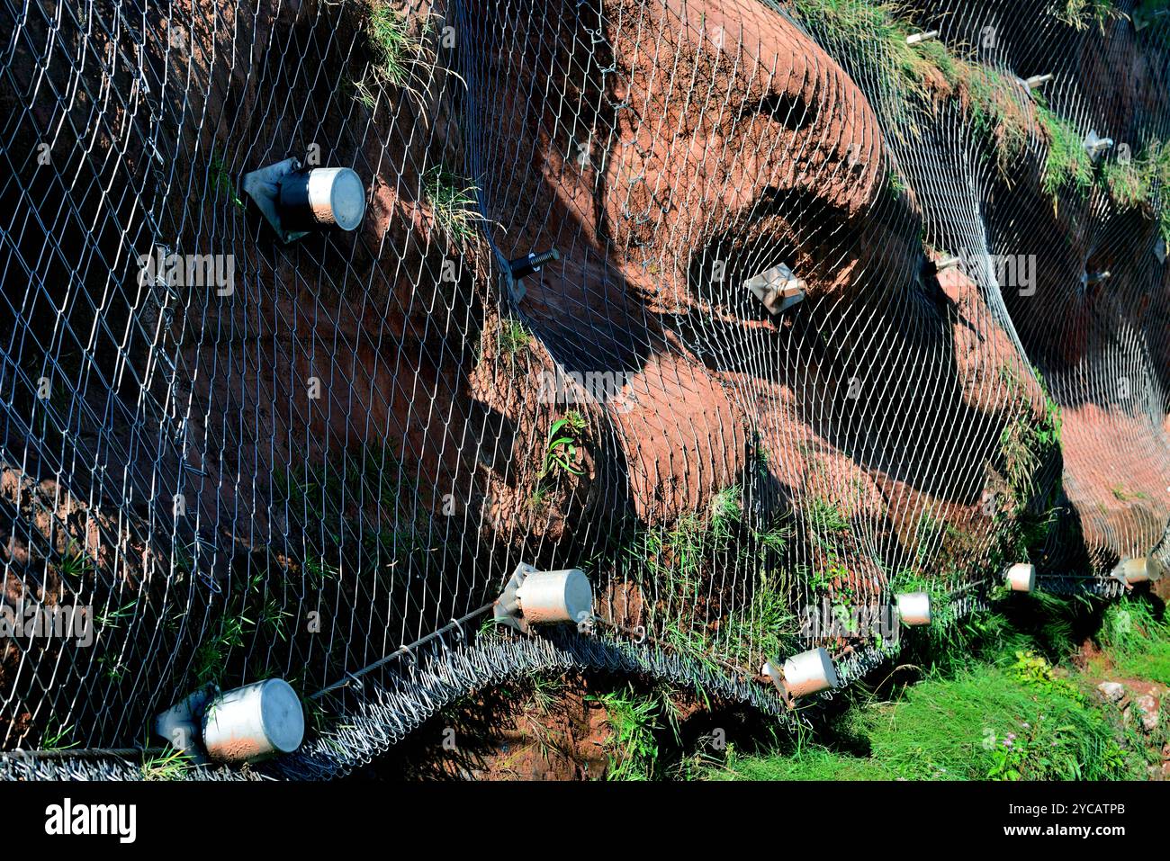 Rock bolts and wire netting supporting unstable red sandstone cliffs ...