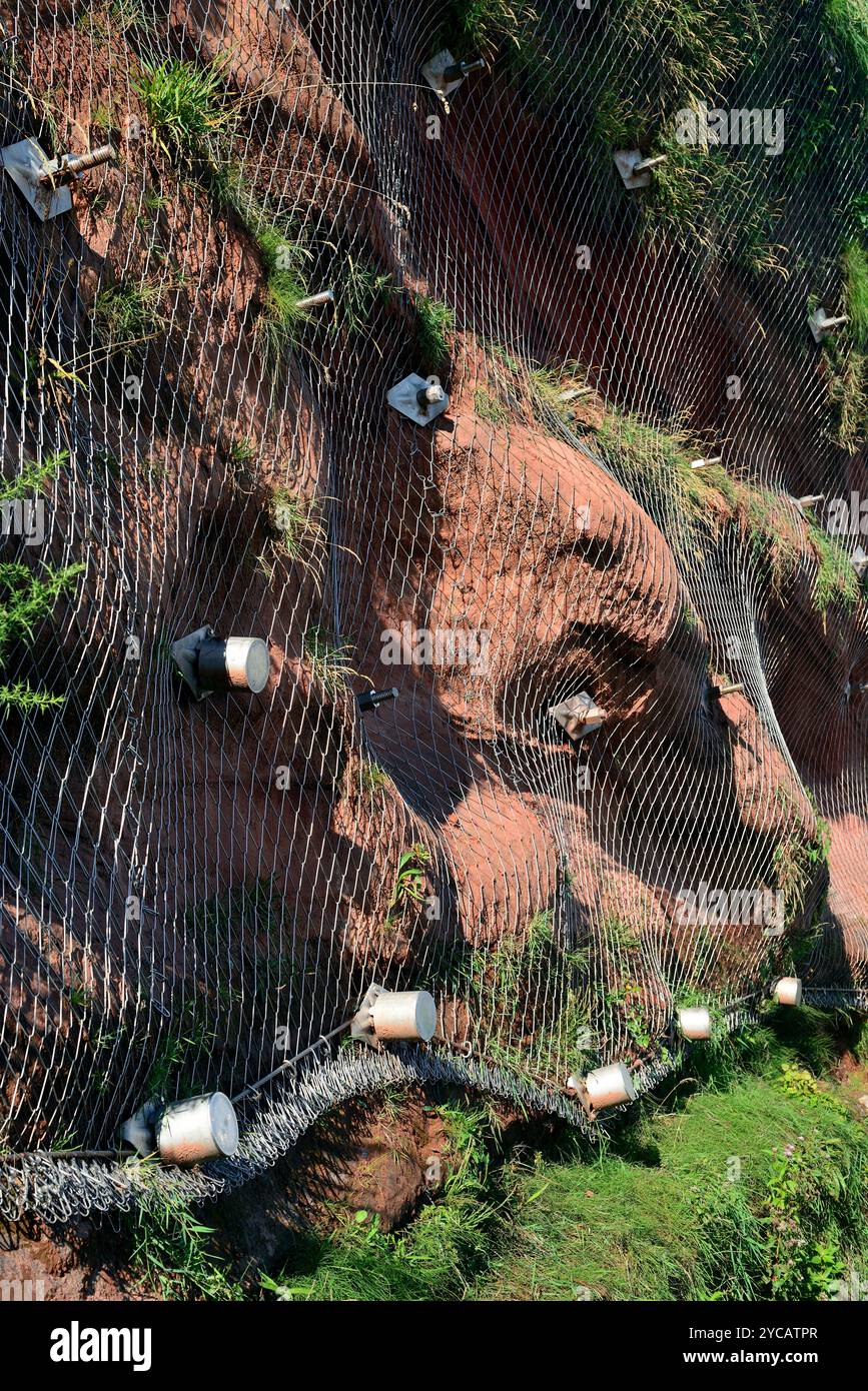 Rock bolts and wire netting supporting unstable red sandstone cliffs ...