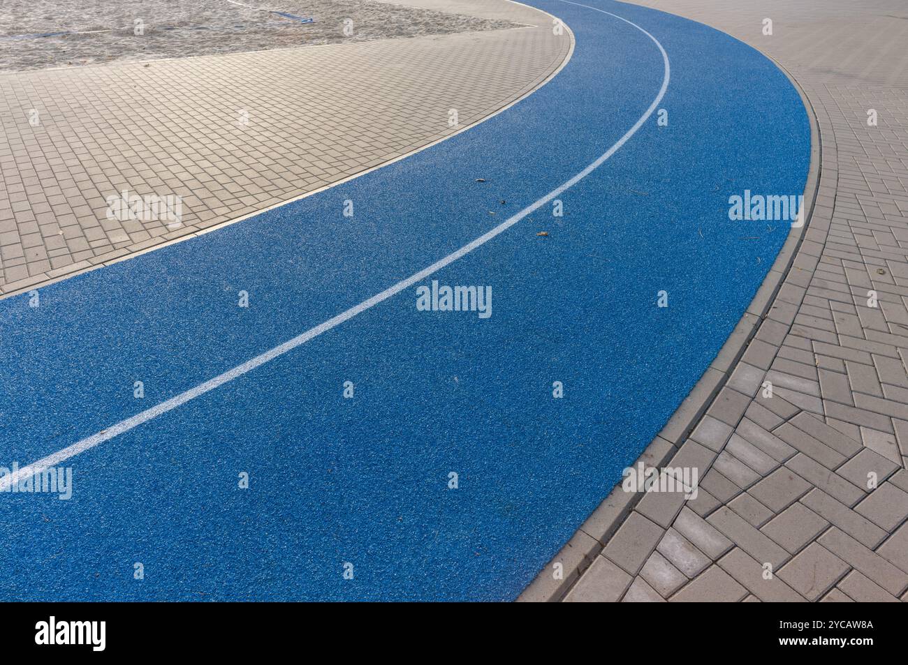 Blue running track curve with white lines surrounded by paving stones ...