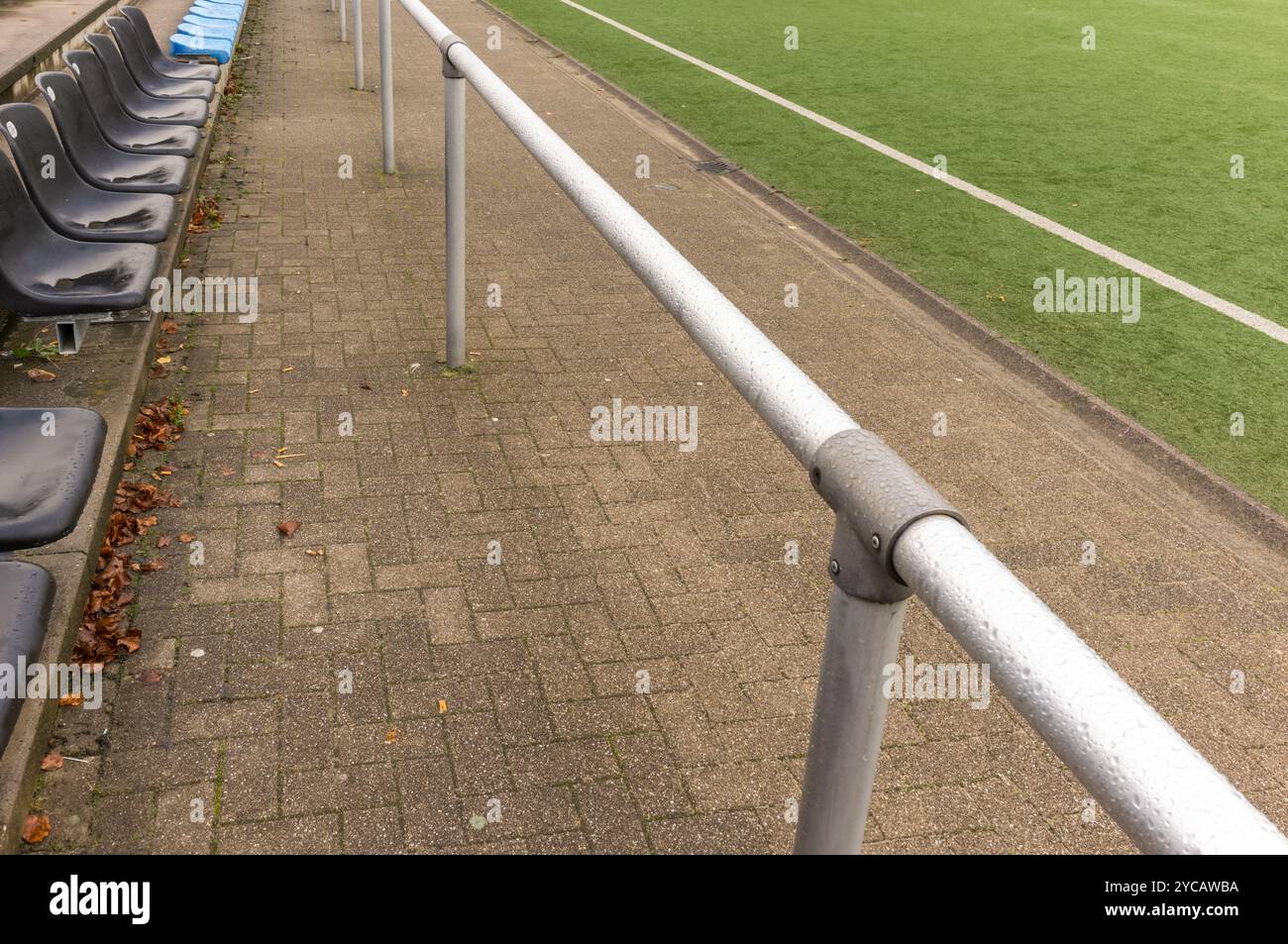 Empty black bleacher seats and a shiny metal railing are overlooking an ...