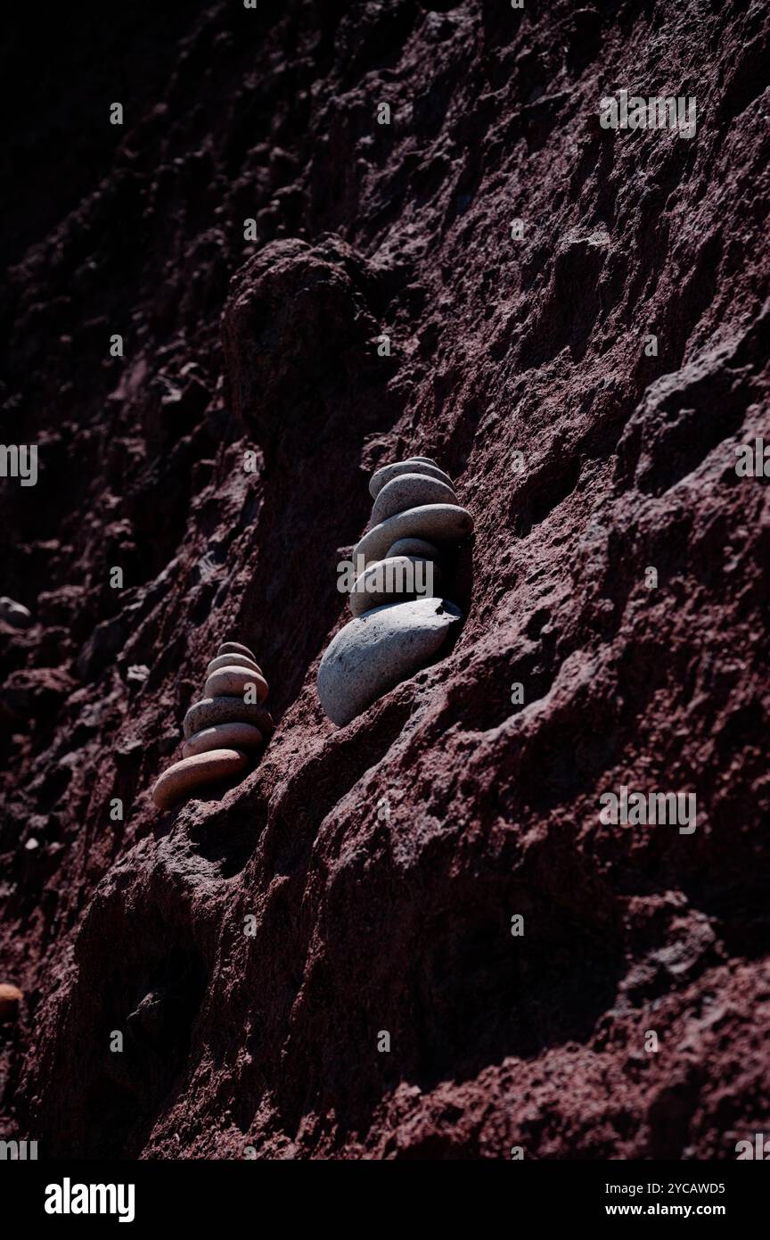 Stacked pebbles nestled into the textured red rock wall of Vereda da ...