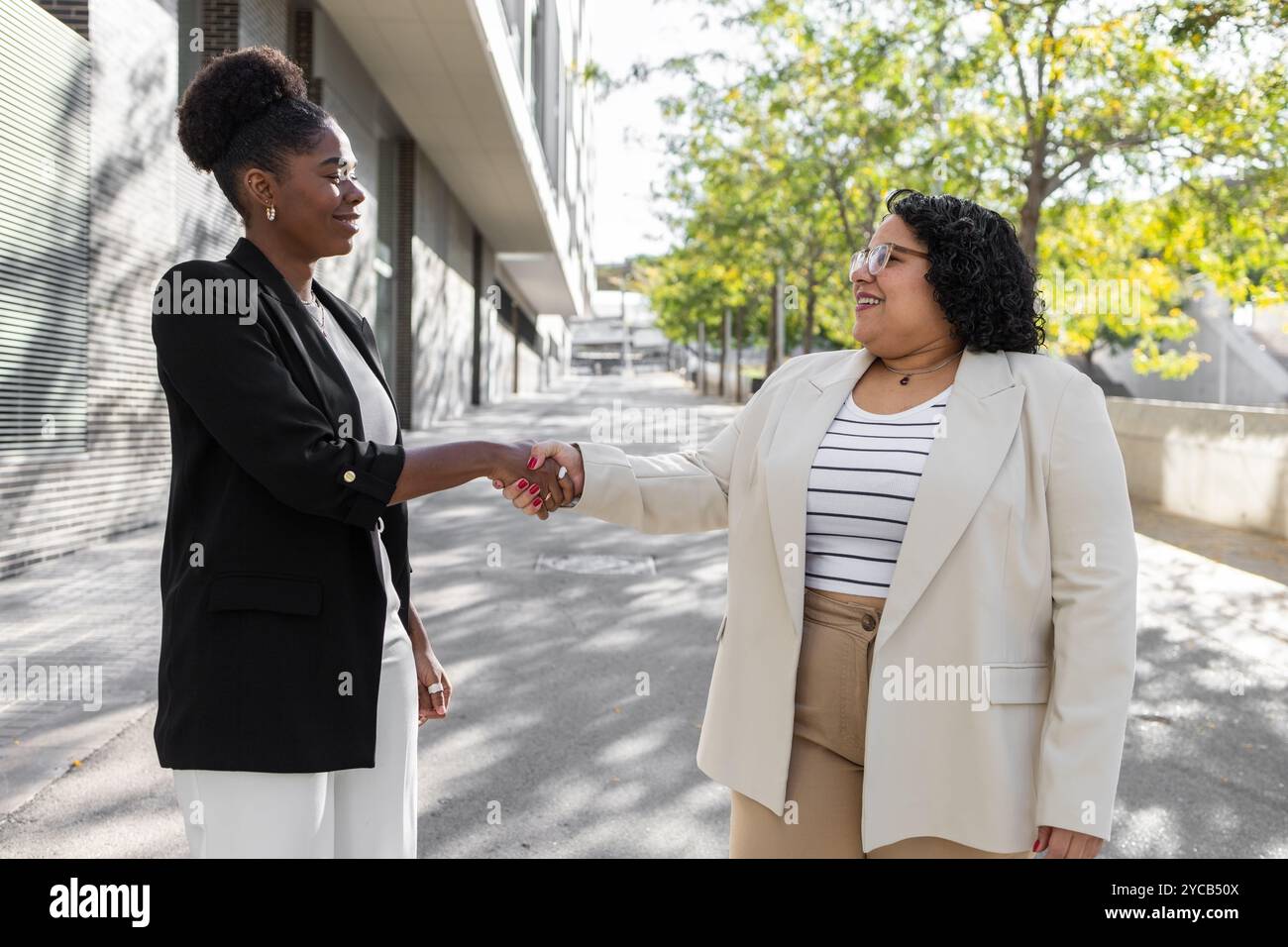 In an urban setting, two professional women, one African American and ...