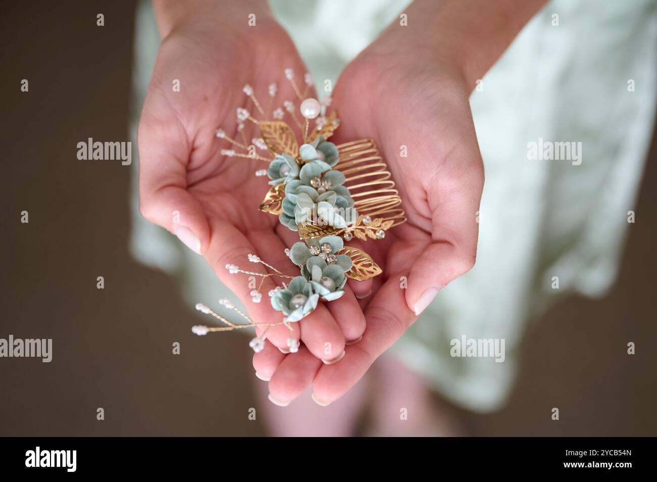 A close-up image showing a bride holding a delicate floral hair ...