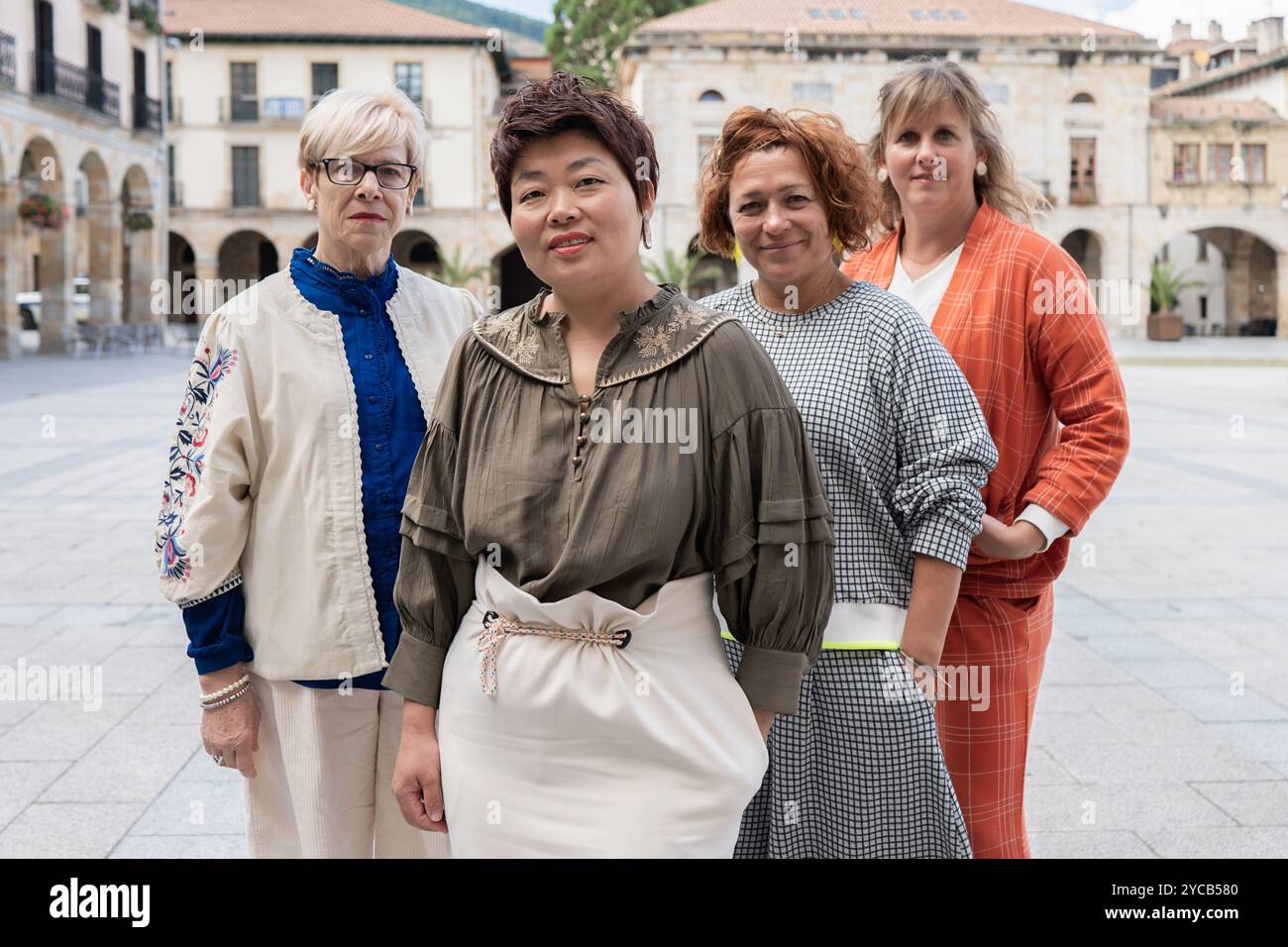 A diverse group of four women stands confidently together in a public ...