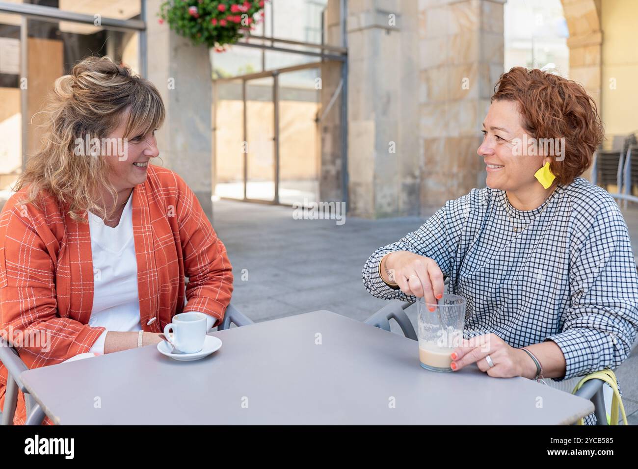 Two joyful women in casual attire share a moment of laughter and ...