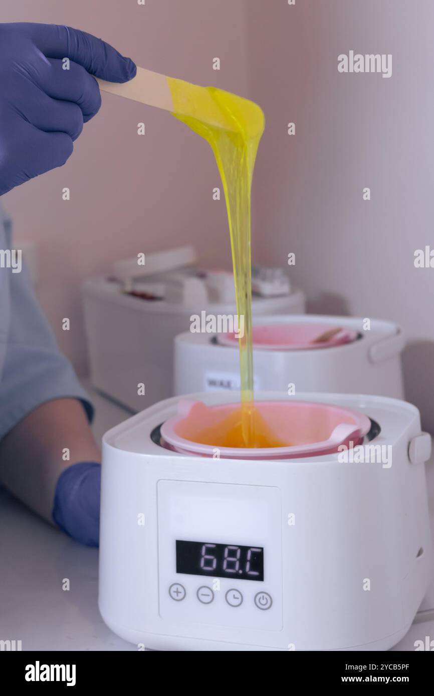 Waxing process in a beauty salon with warm wax and an applicator in use ...