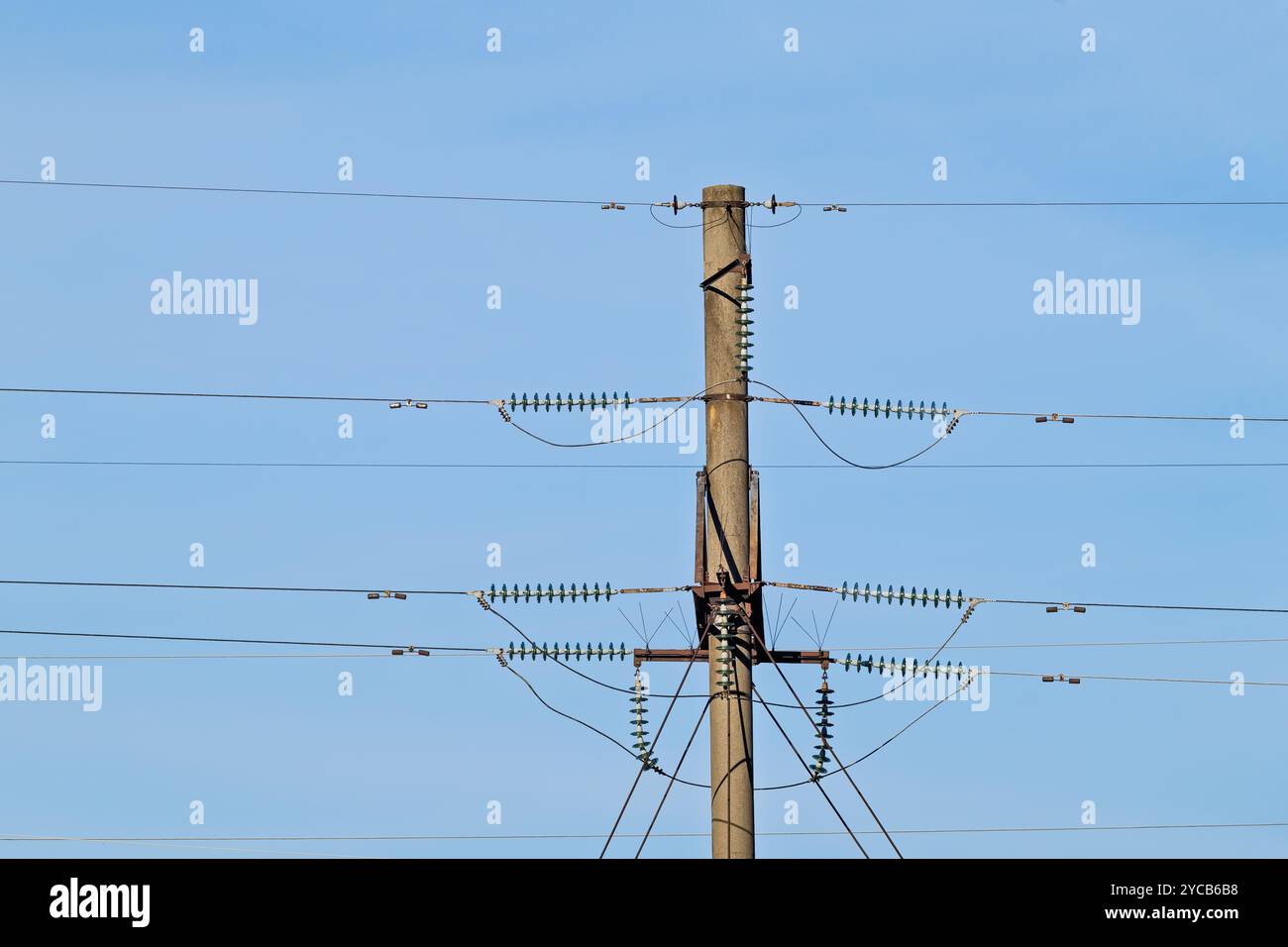Urban utility pole with tangled power lines against a clear blue sky ...