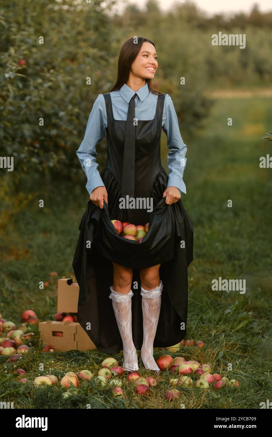 Beautiful Asian woman in stylish clothes with apples in the garden. A ...