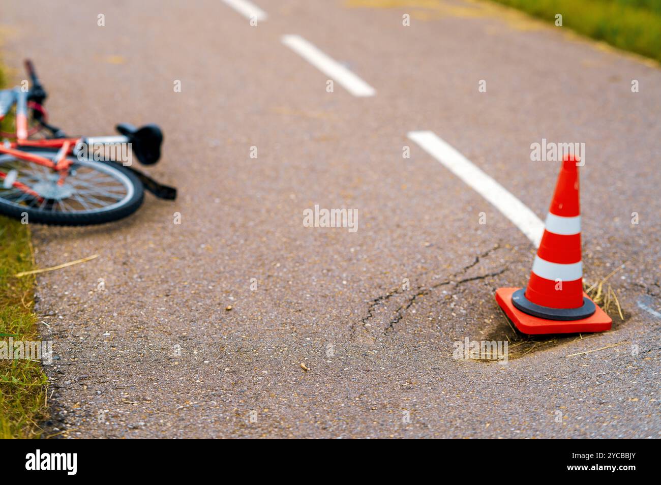 traffic cone and pothole in asphalt, dropped bike in the background ...