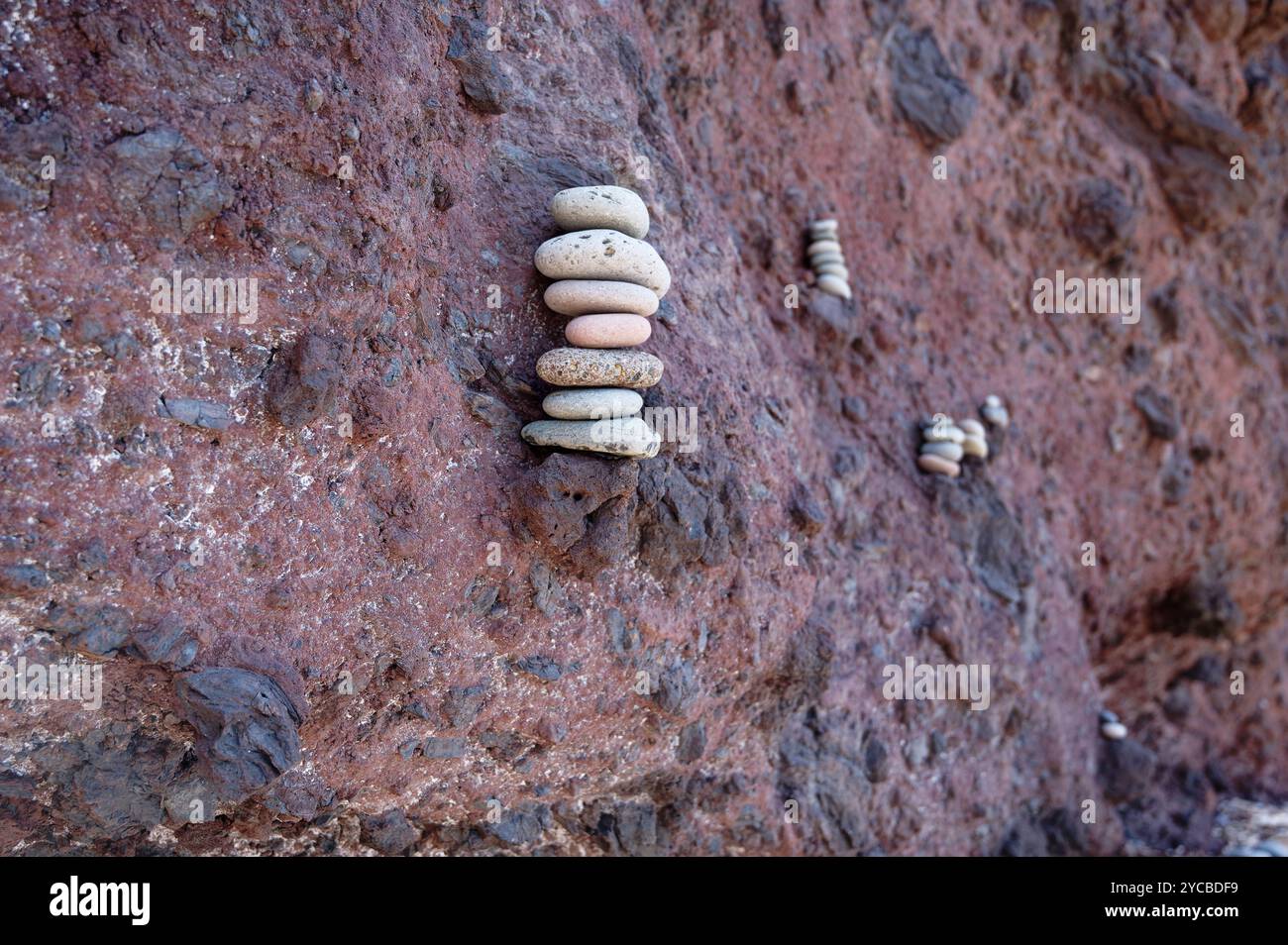 Stacked pebbles carefully balanced on the rugged red rock wall of ...