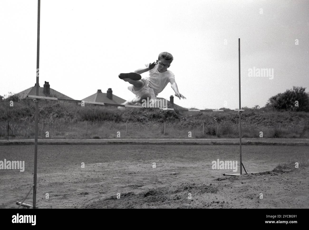 1960s, historical, a teenage schoolboy doing the high jump, jumping ...