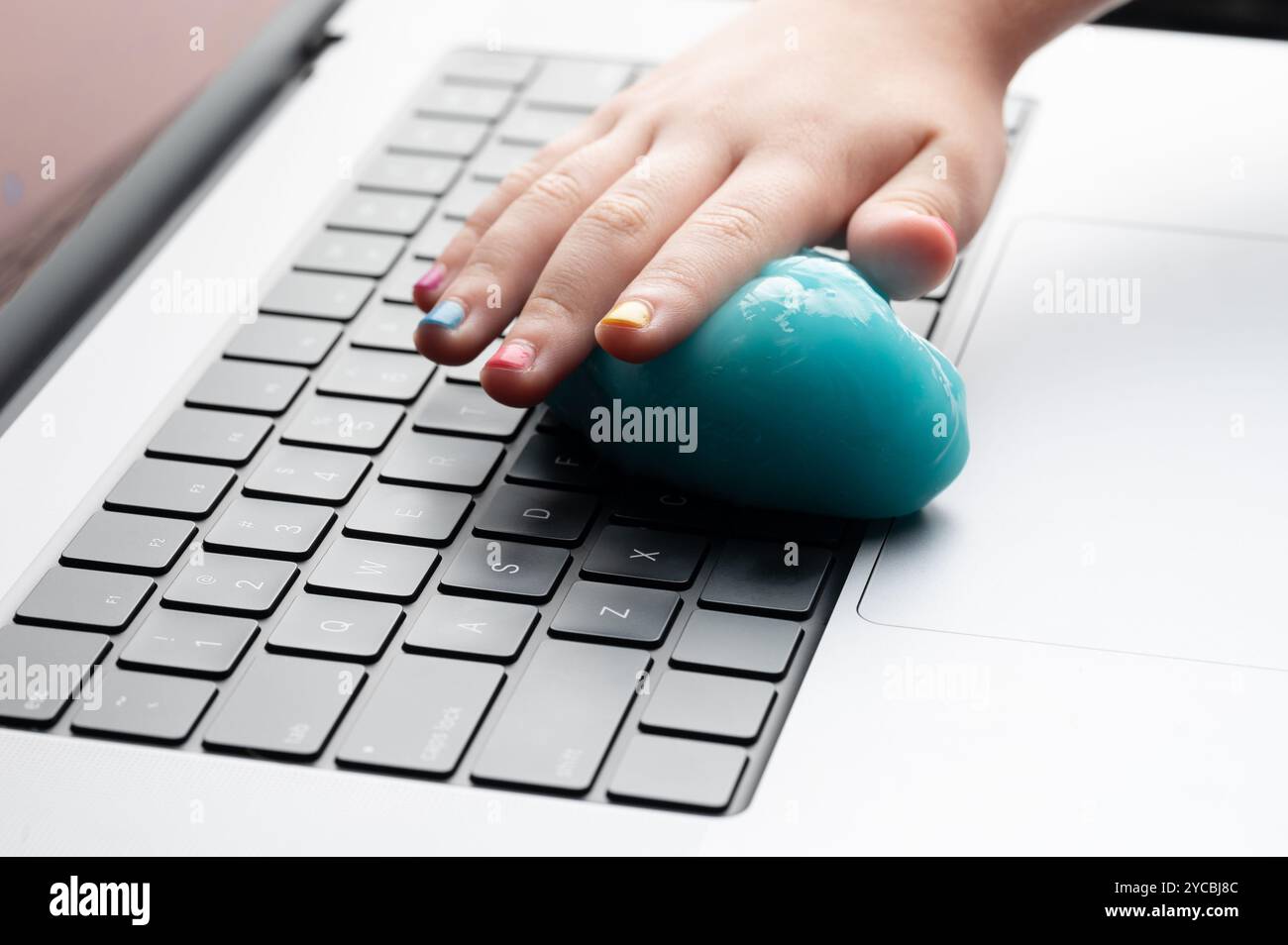 Blue gel cleaning laptop keyboard in hand with colorful nails close up ...