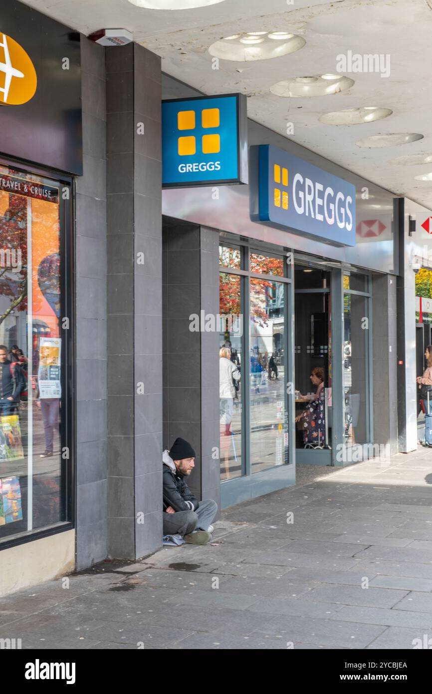 homeless man sitting in a doorway outside of a Greggs sandwich shop on ...