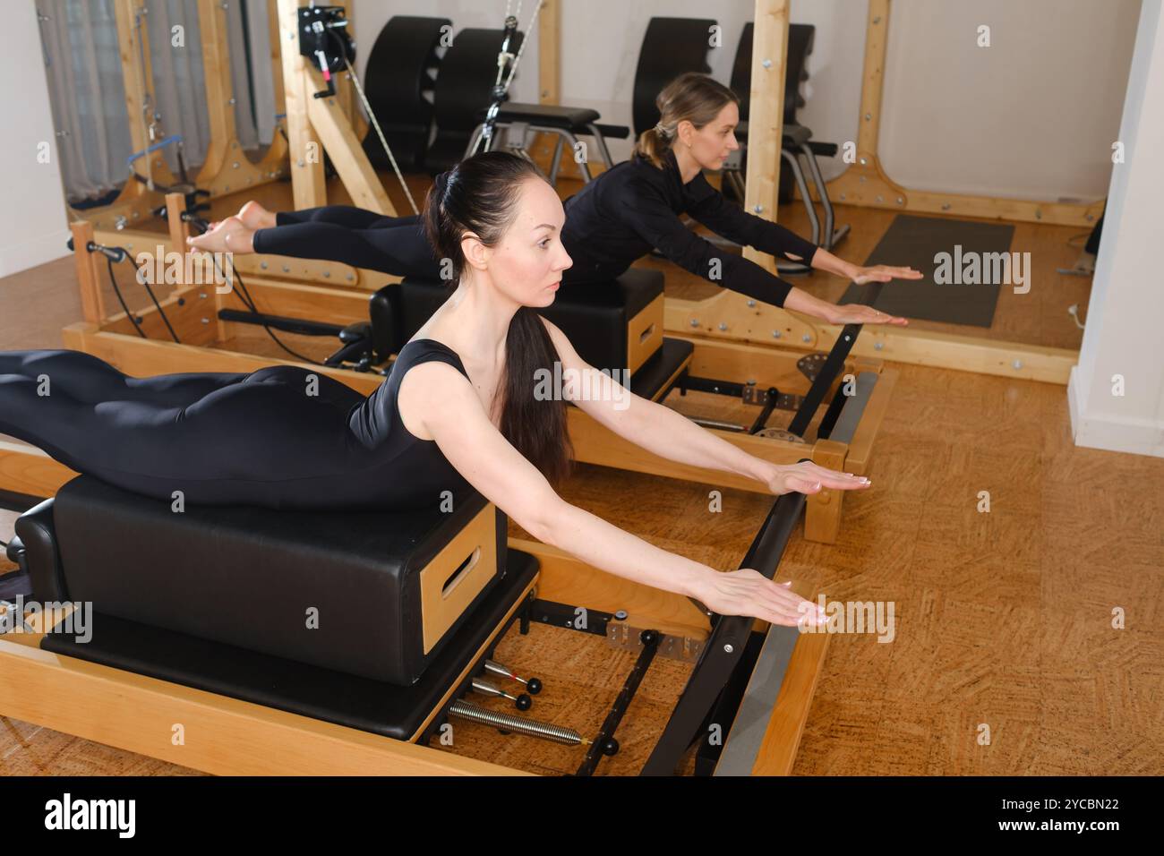 Two women are practicing physical fitness exercises on a Pilates ...