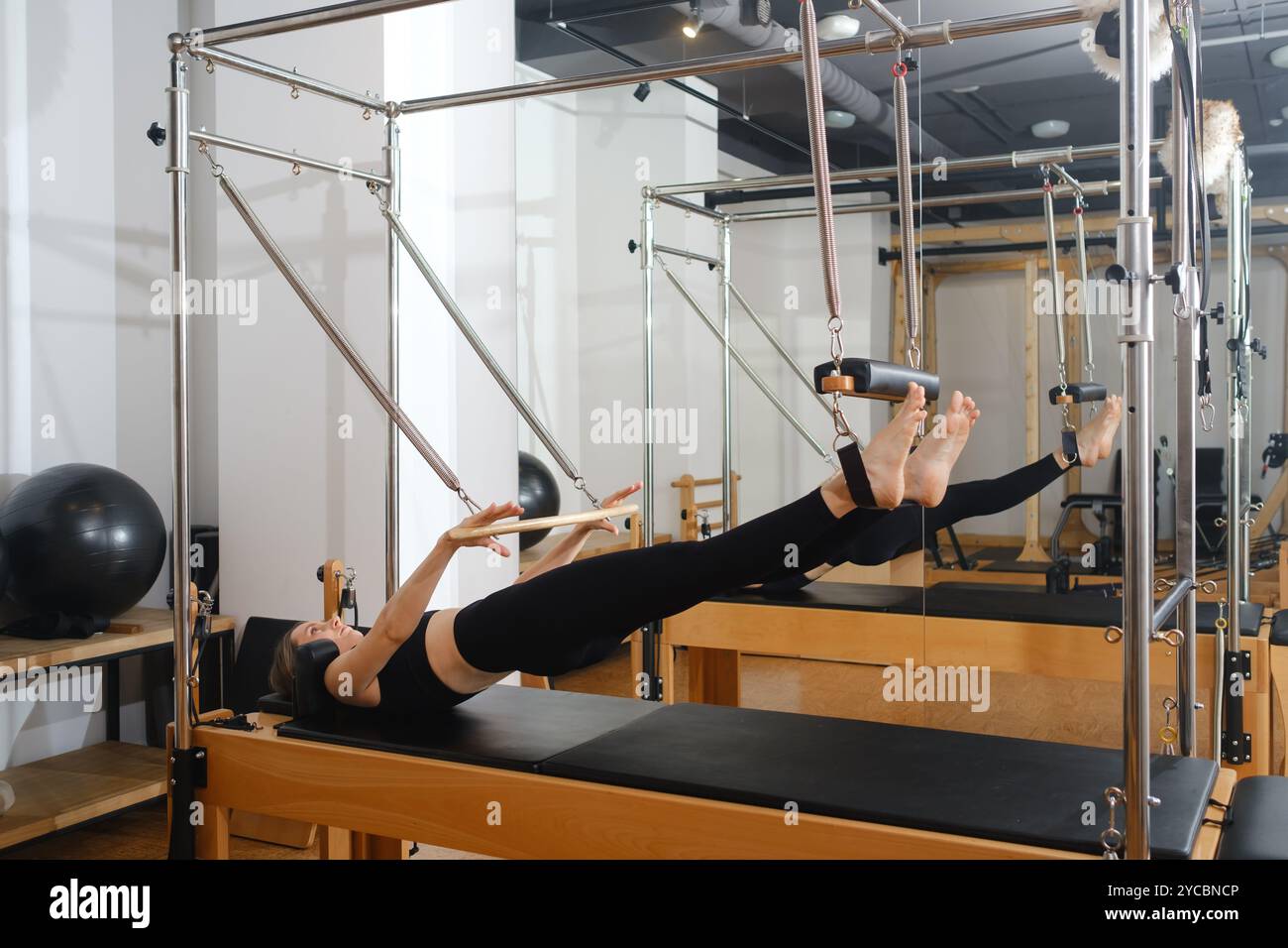Young girl doing Pilates on trapeze table in the gym. Beautiful slim ...