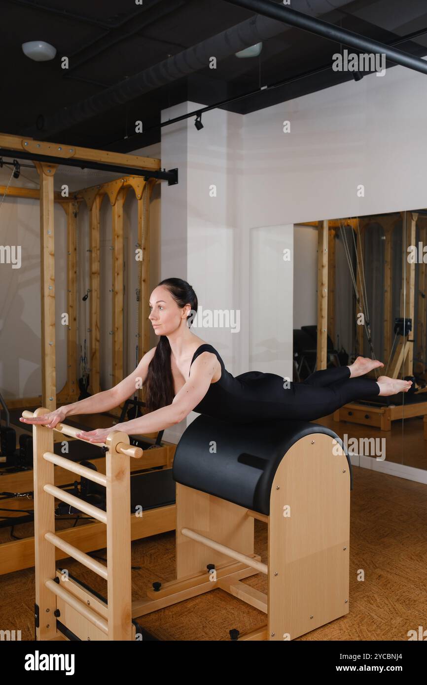 Young girl doing Pilates barre in a gym. Beautiful slim woman in black ...