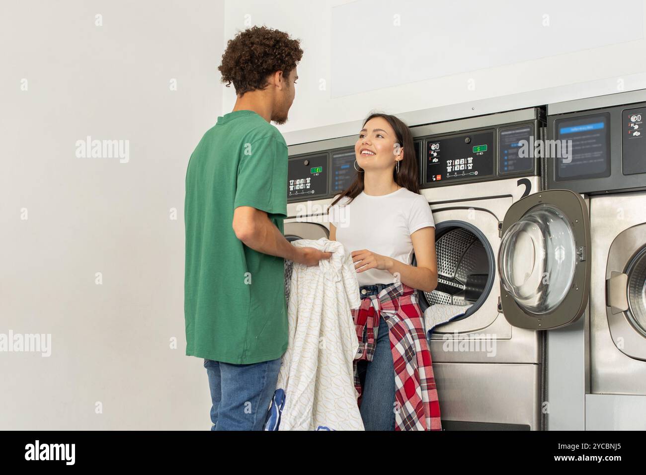 Couple interacting at a laundromat while doing laundry together in the ...
