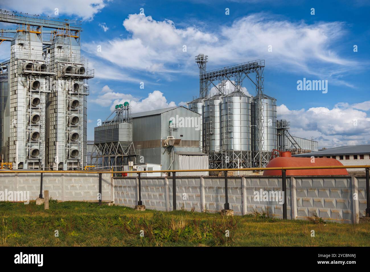large grain elevator with multiple cylindrical metal silos, structural ...