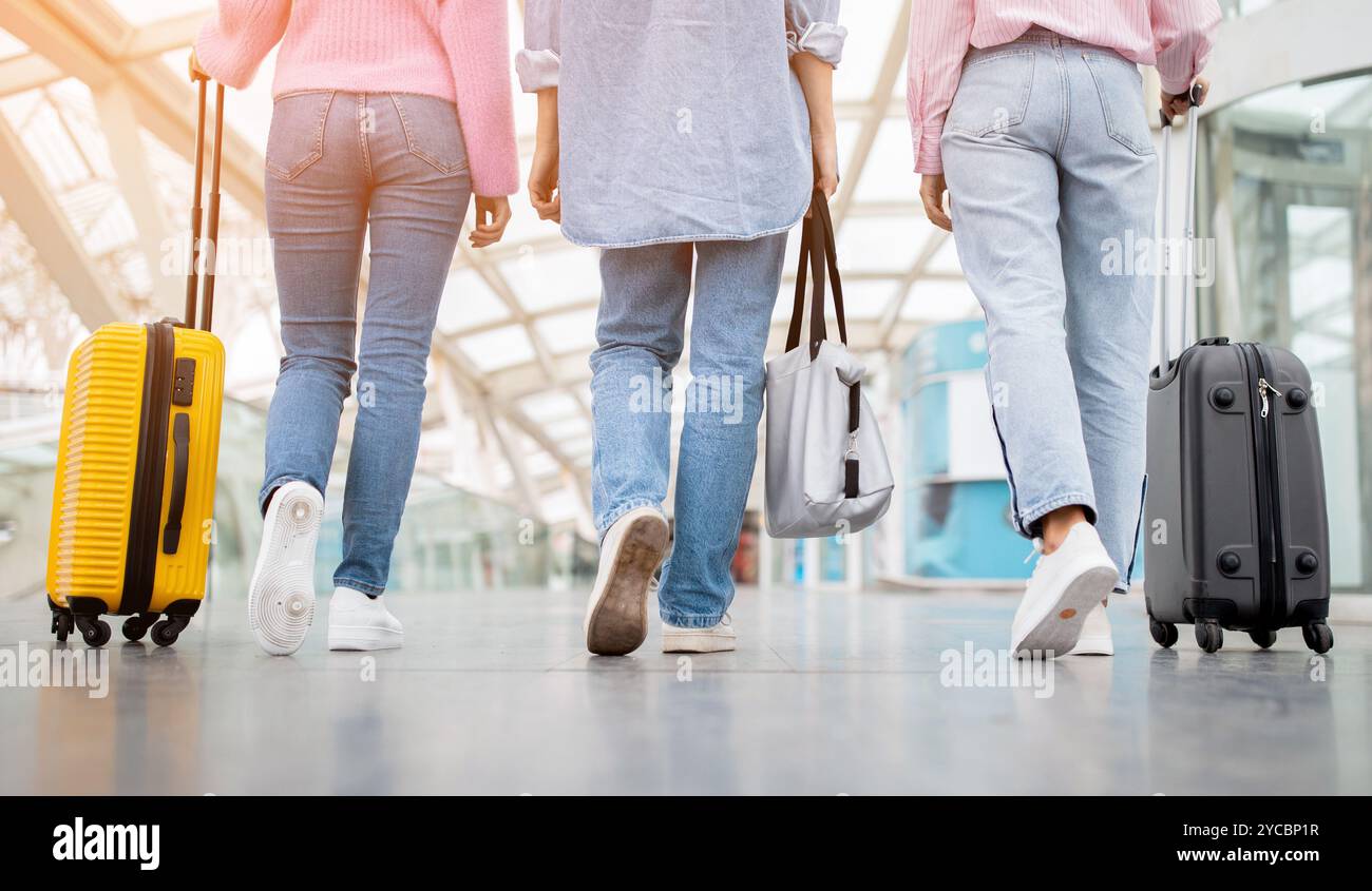 Traveling companions walking with luggage in modern airport terminal ...