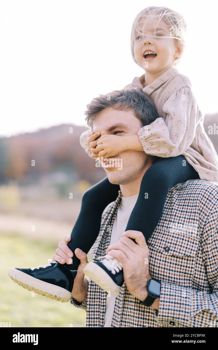 Little laughing girl covered her smiling dad nose with her palms while ...