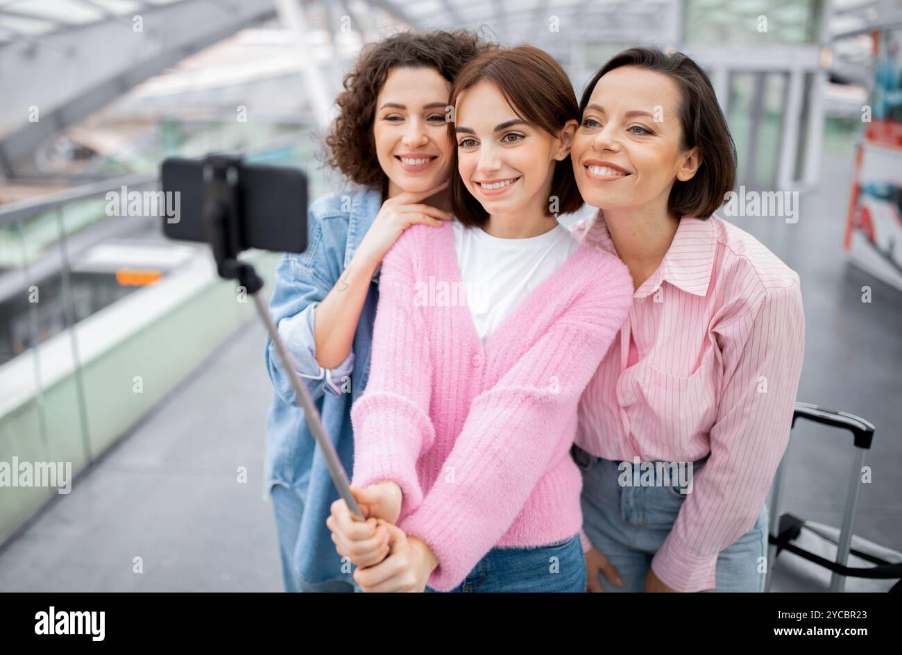 Three friends take a selfie together in a modern building during the ...