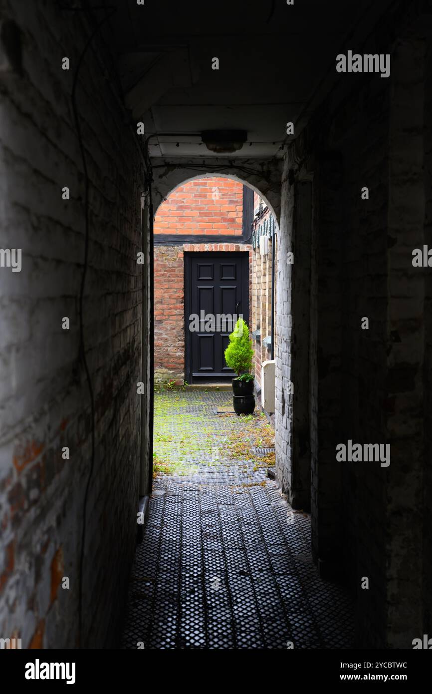 View through a dark passageway to a courtyard with a black door Stock ...