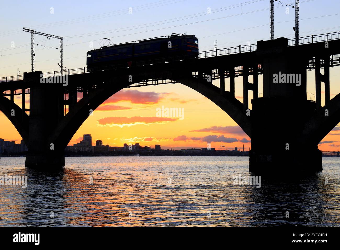 Train, diesel locomotive goes on the arched railway bridge on the river ...