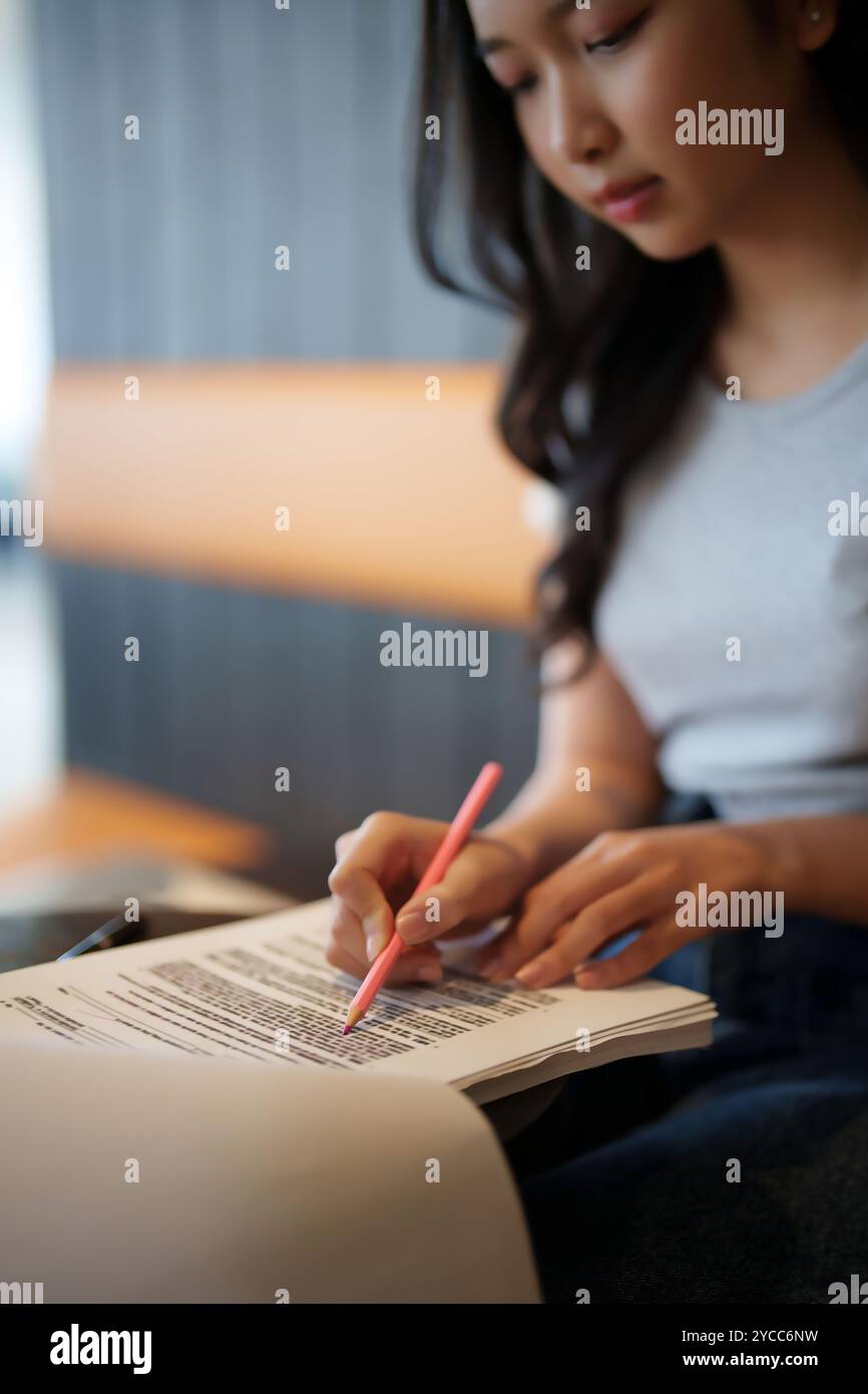Asian teenage student woman using color pencil to highlight data in ...