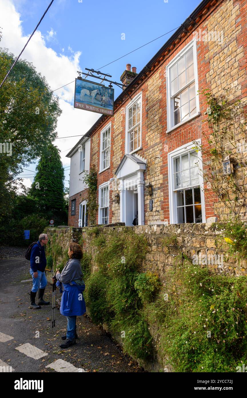 Two walkers stand outside the pretty White Horse pub in Sutton village ...