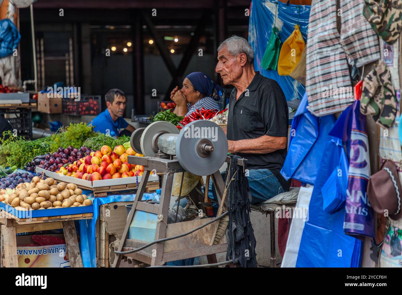 A scissor grinder and fruit vendor at the Dezerter Bazaar in Tiblisi ...