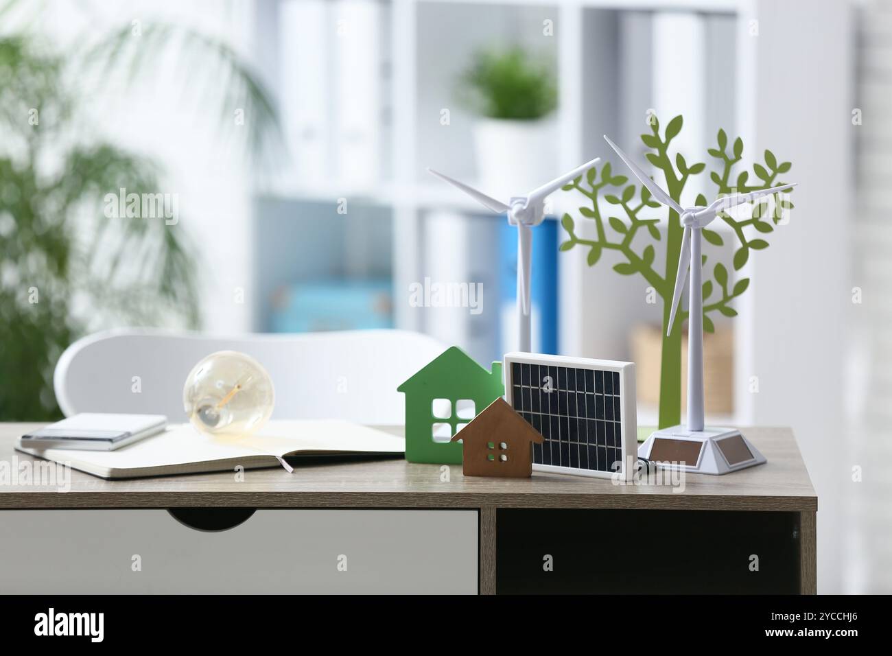 Wind turbine models with solar panel and house figures on table in ...