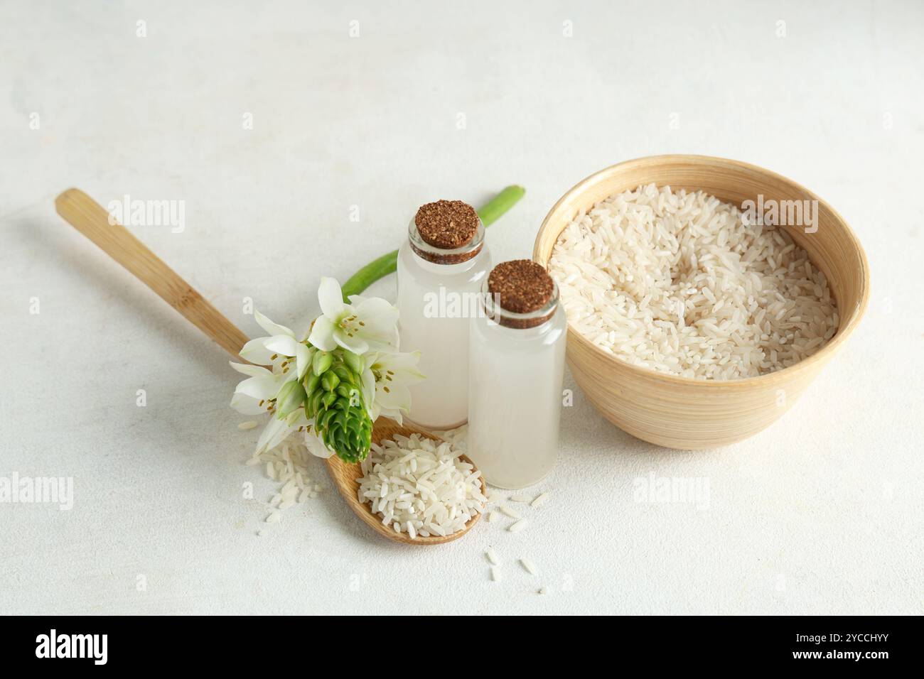 Bottles with rice water, grains and flower on light background Stock ...
