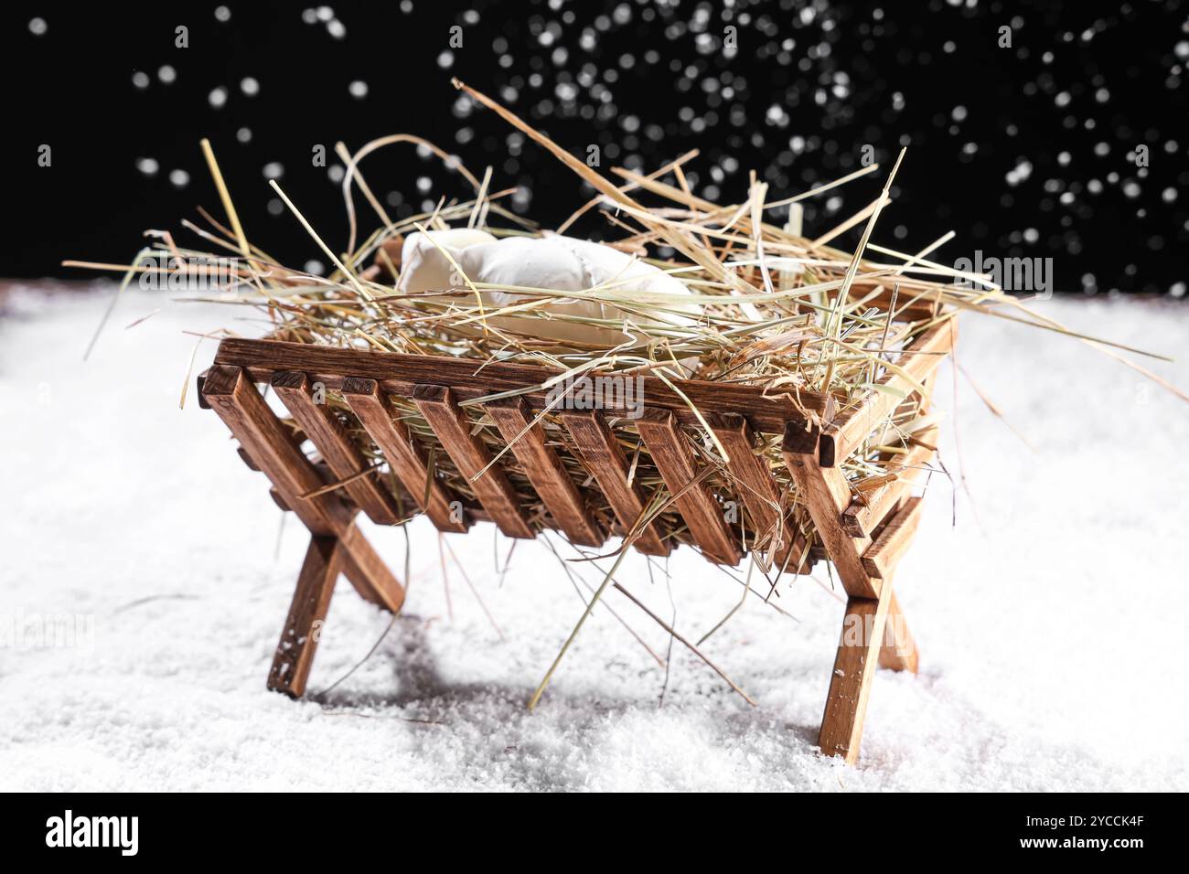 Manger with baby Jesus and hay on snow against dark background Stock ...