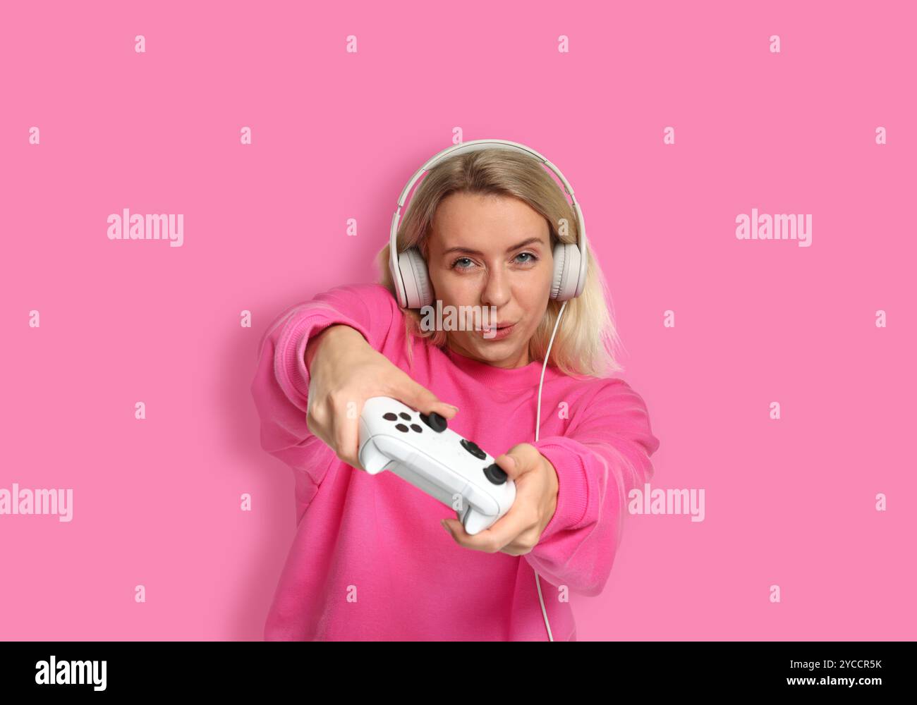 Woman playing video games with controller on pink background Stock ...