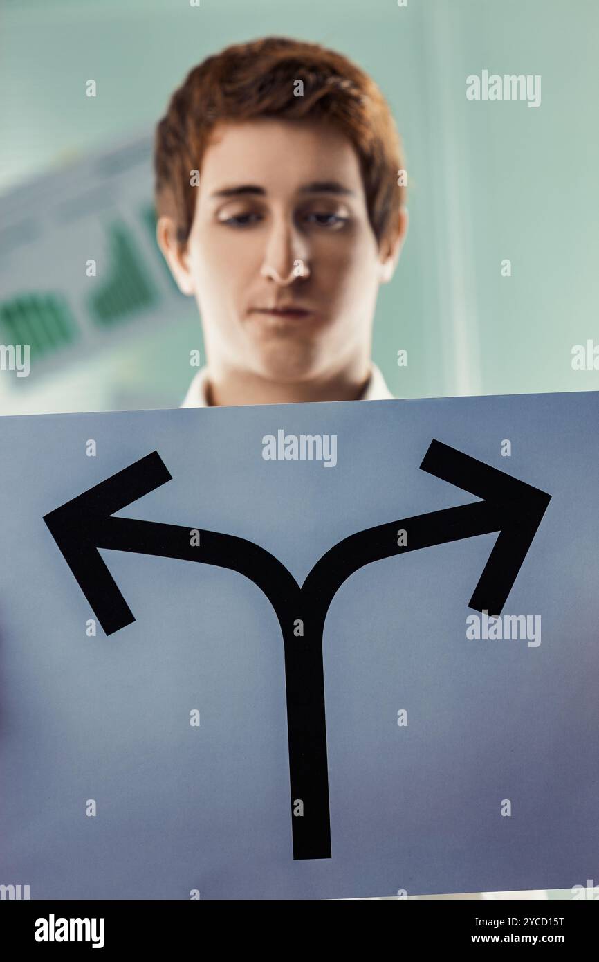 Businessman is holding a sign with arrows pointing in opposite ...