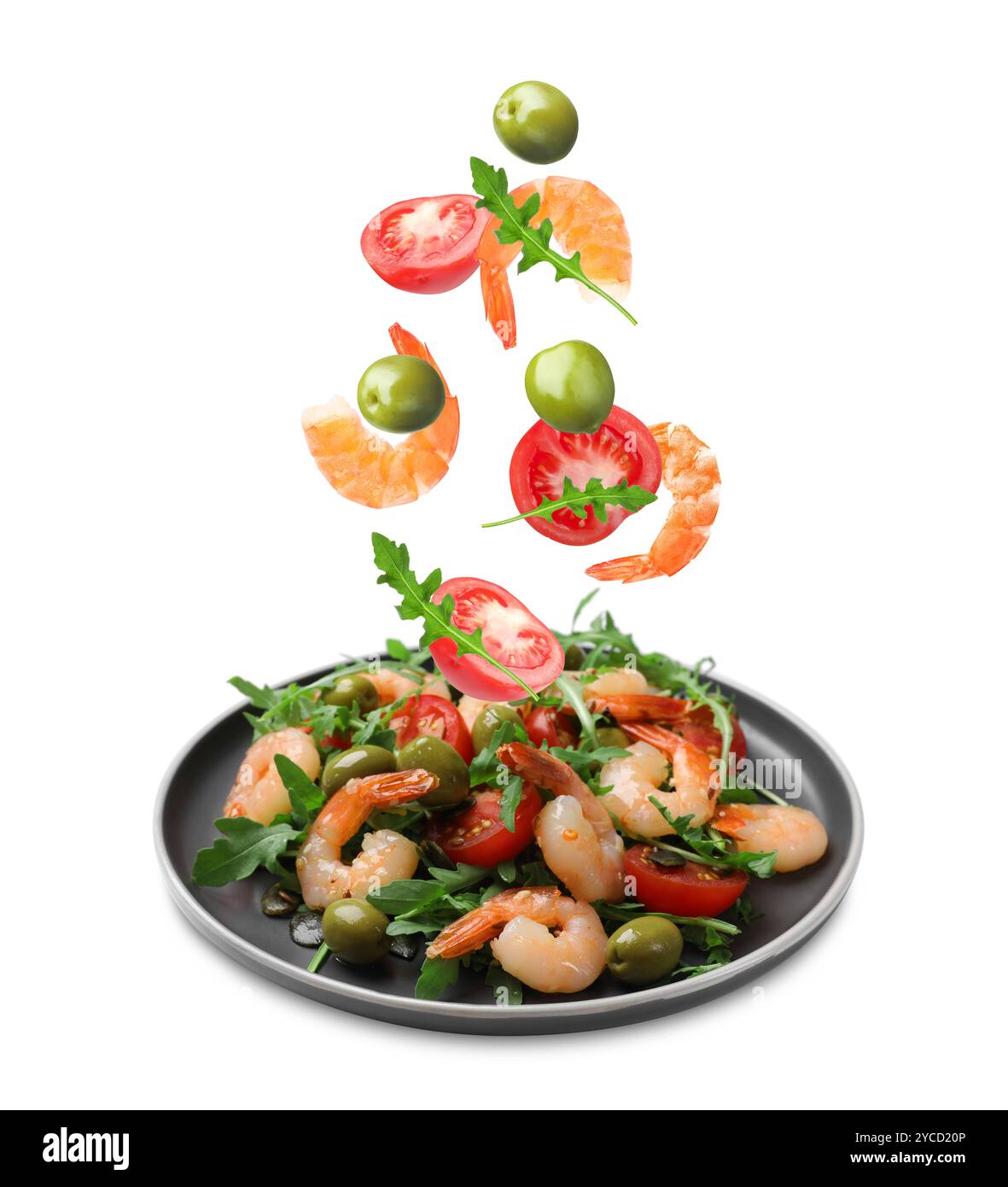 Shrimps and other ingredients falling onto plate on white background ...