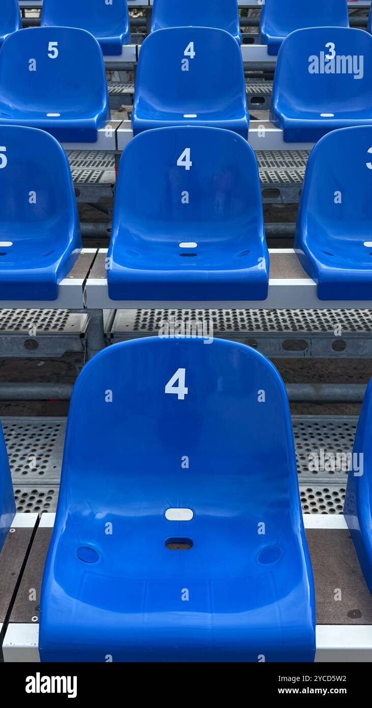 Close-up of blue plastic stadium seats with the number 4. The organized ...