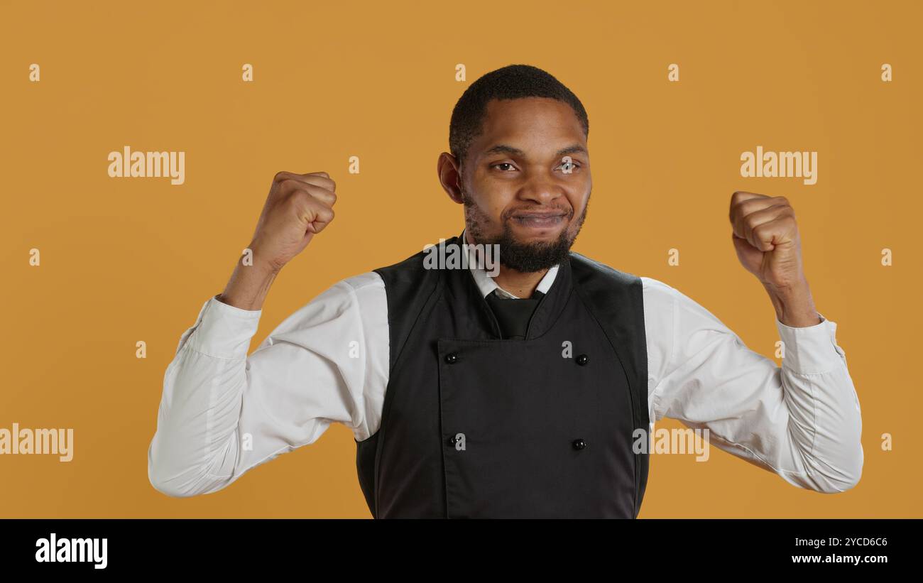 Waiter flexing his muscles and showing his strength in studio, acting ...
