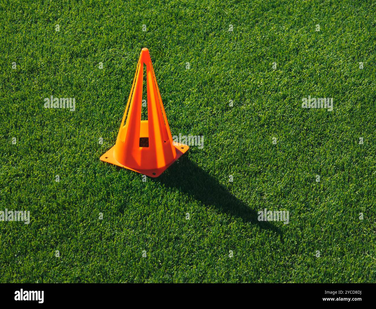 An orange sports practice pylon on artificial turf Stock Photo - Alamy