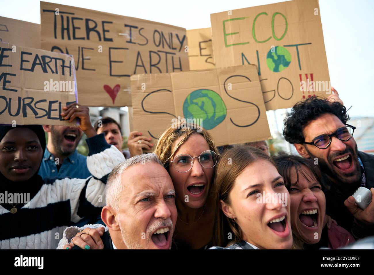 Cardboard banners written against climate change holding diverse group ...