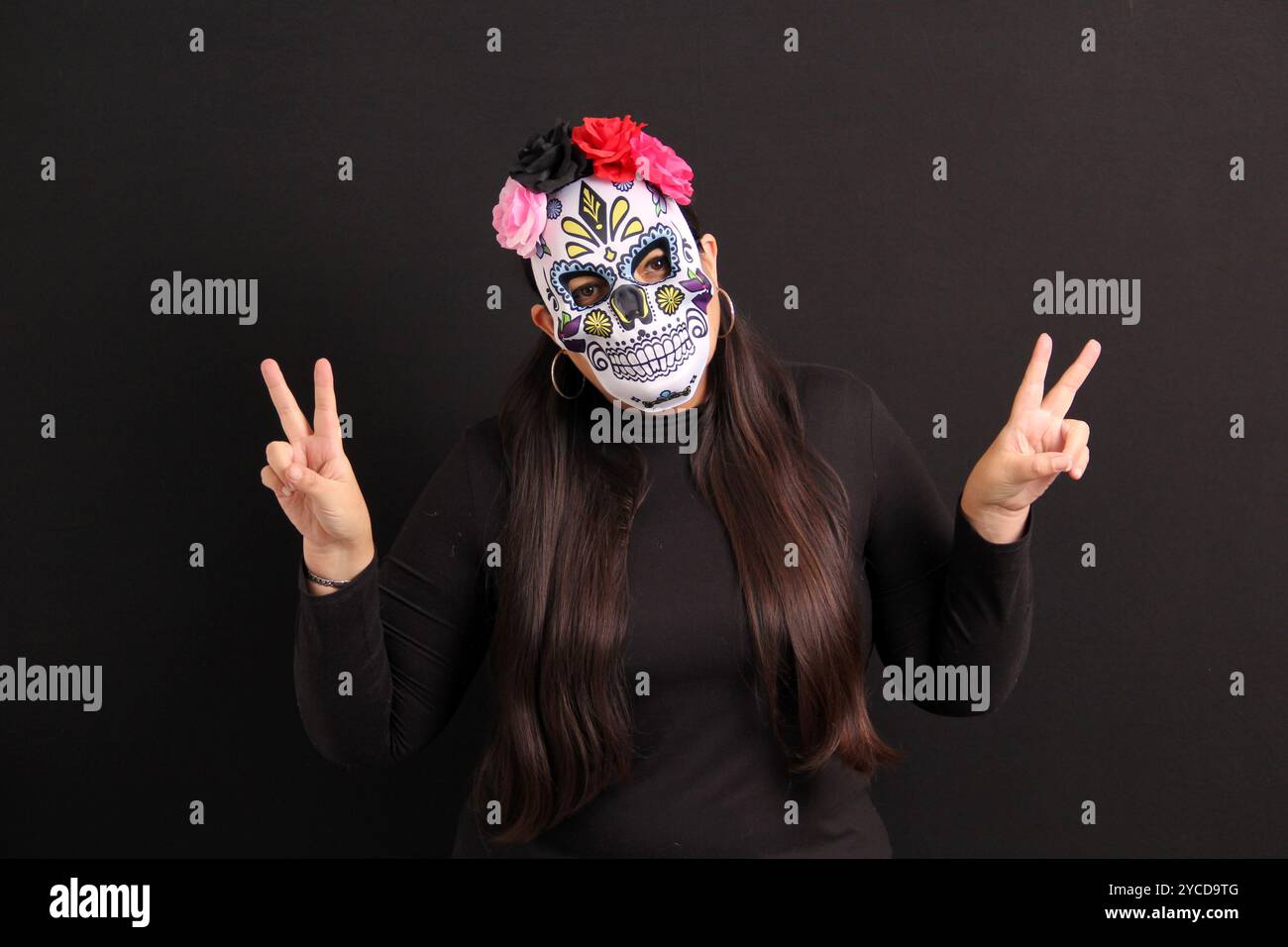 Mexican adult woman with catrina mask shows the sign of love and peace ...
