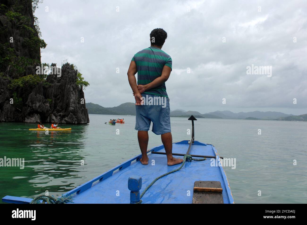 Man on the bow of a tourist boat preparing to throw anchor overboard ...