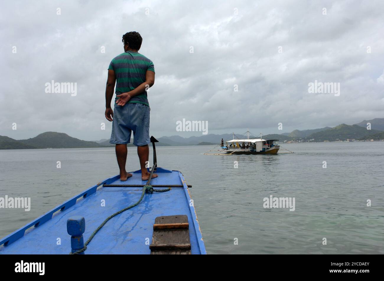 Man on the bow of a tourist boat preparing to throw anchor overboard ...